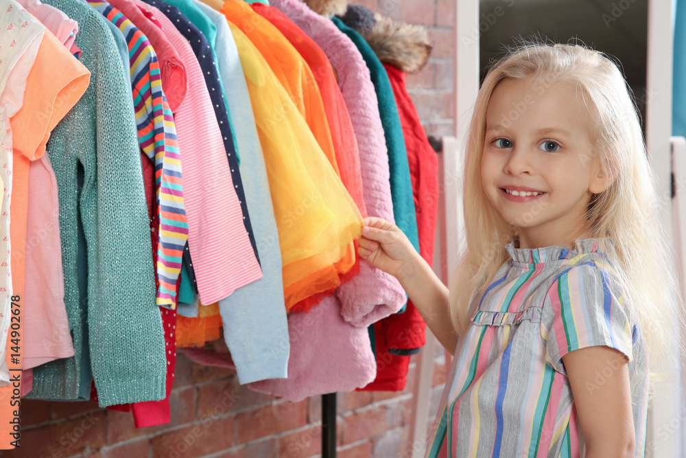 Cute little girl choosing clothes in dressing room Stock Photo | Adobe ...