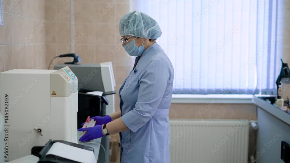 Professional female medical scientist in blue scrubs, mask, cap and ...