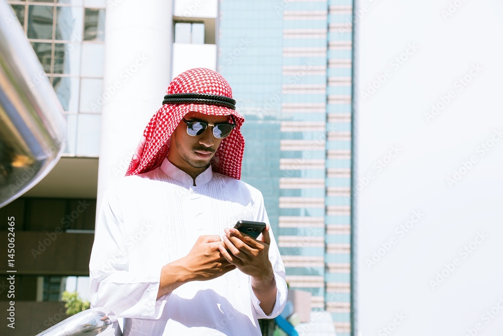Young Arabian man is holding a smart phone in his hand with modern ...