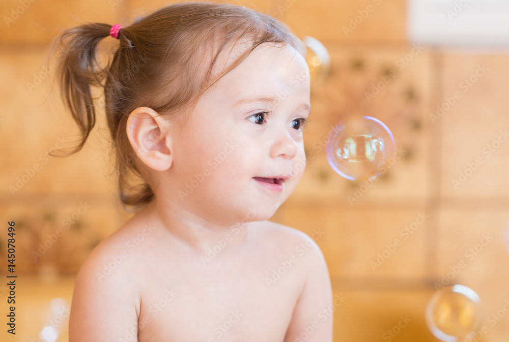 Playing with bubbles.Happy little girl in bathtub playing with soap ...