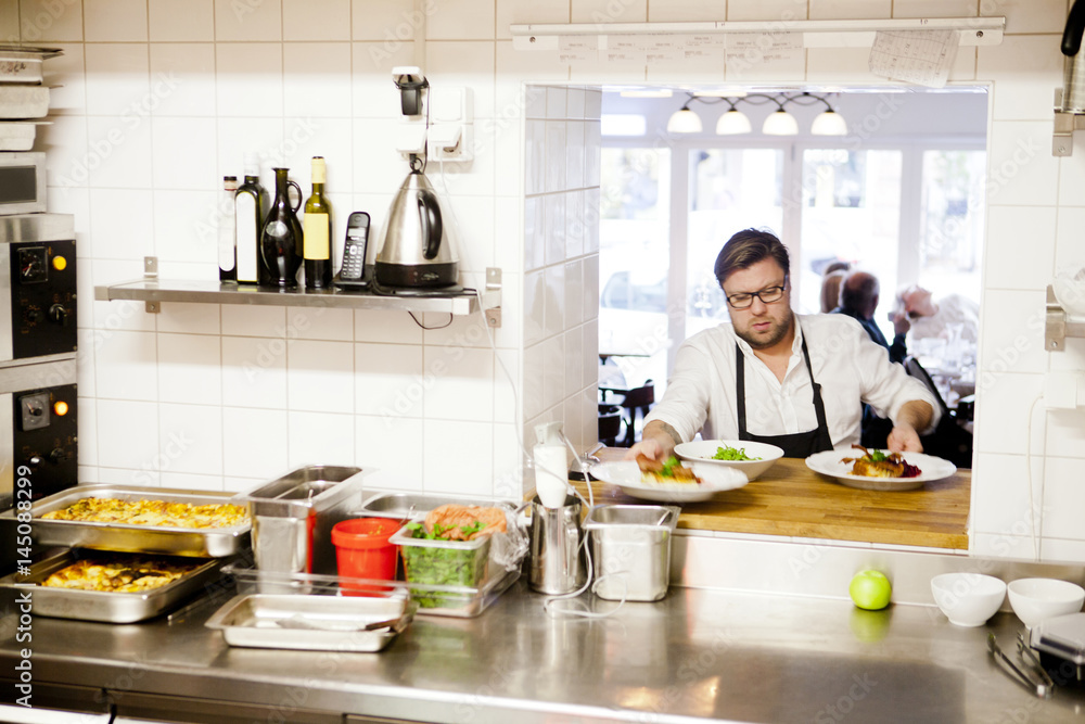 Chef holding serving dishes at commercial kitchen counter Stock Photo ...
