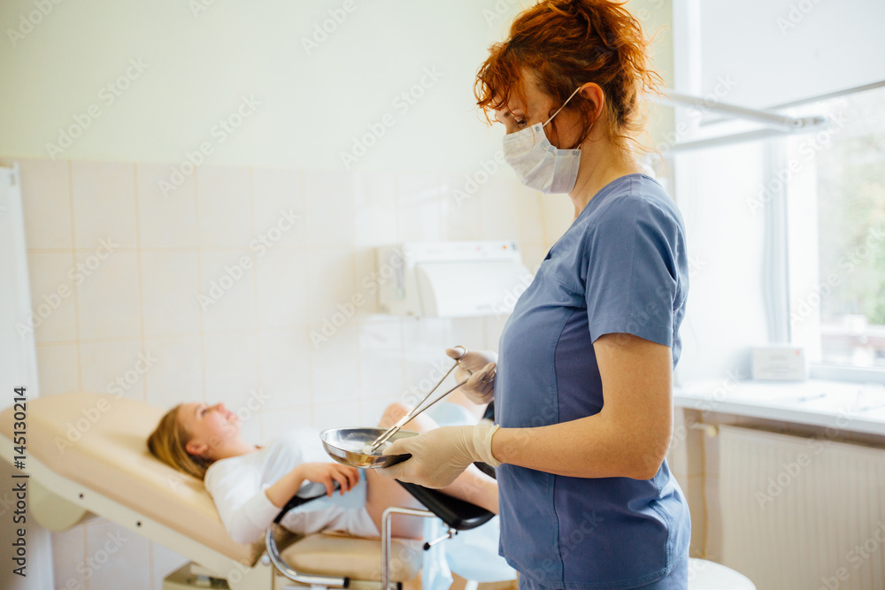 Red hair female doctor holding tool in steel basin in front of the ...