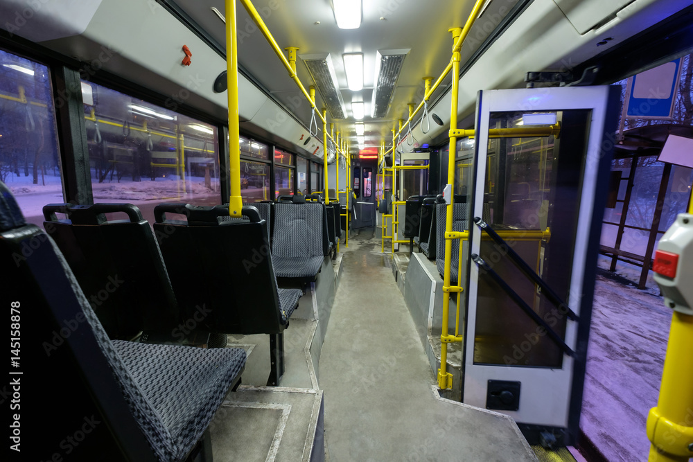 Interior of modern city trolley bus in back part with open doors on bus ...