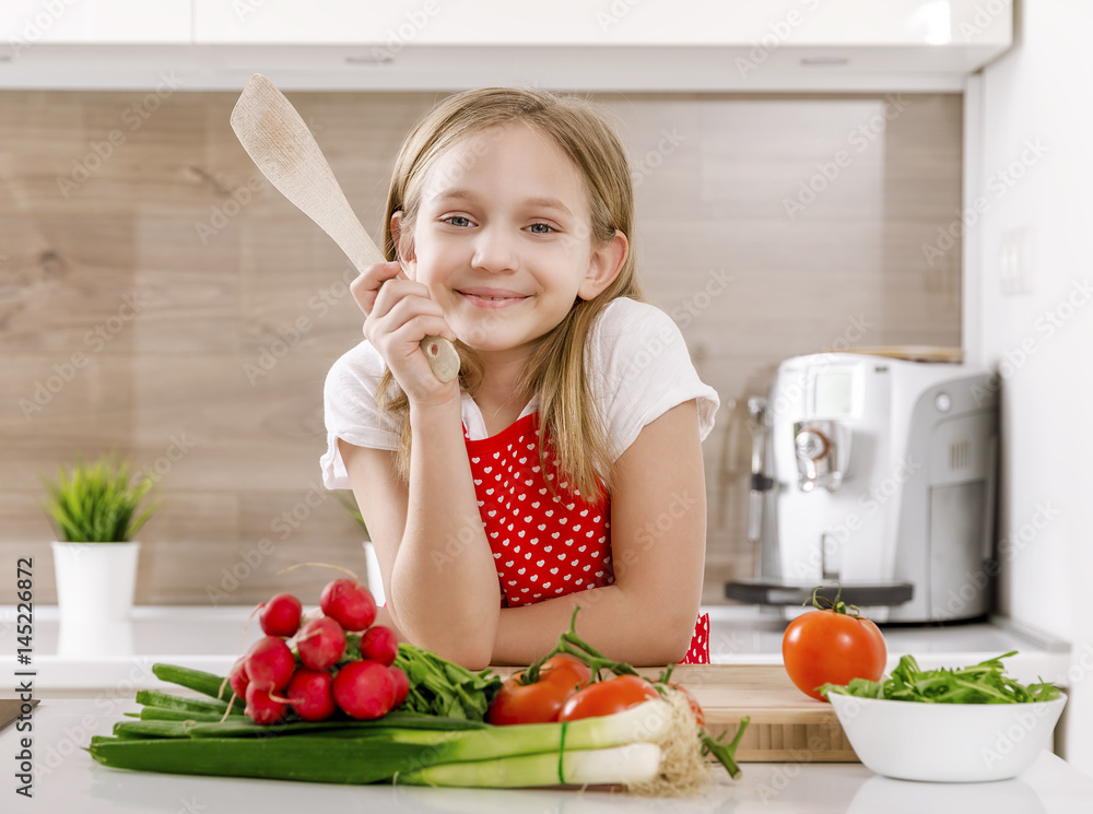 Happy little girl cooking in the kitchen with vegetables Stock Photo ...