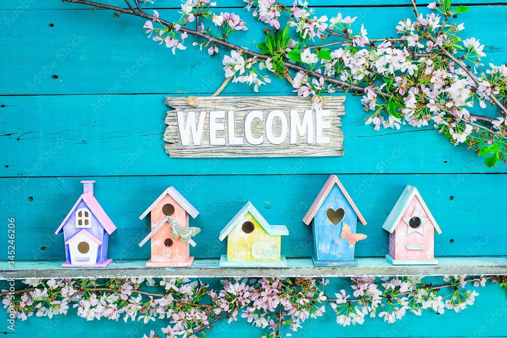 Welcome sign hanging on blue background with flowers and birdhouses ...