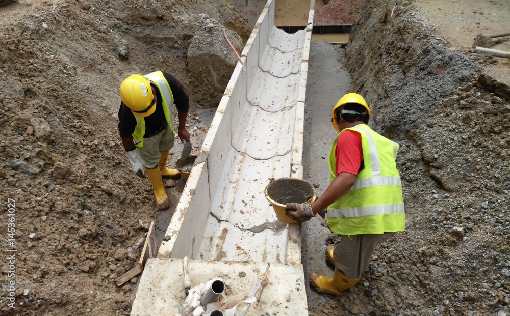 Construction workers installing precast u-shape concrete drain at the ...