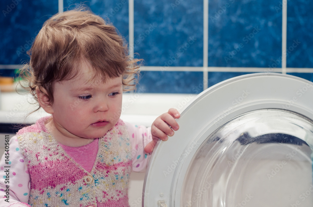 baby puts linen in washing machine Stock Photo | Adobe Stock
