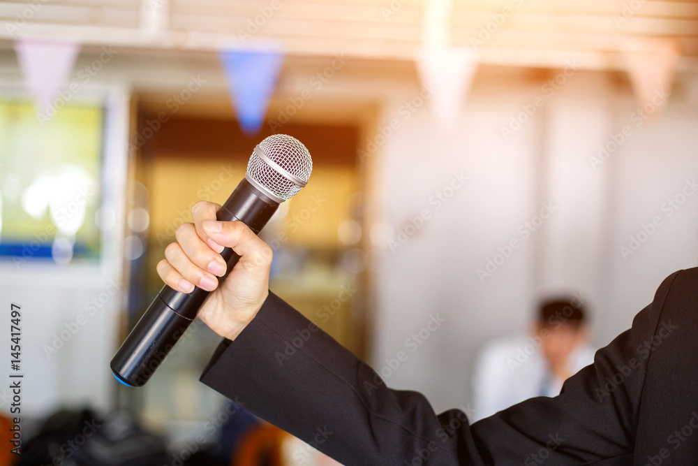 Fotka „Man in business suit holding a microphone conducting a business ...