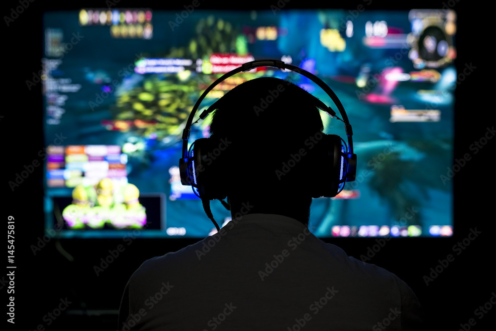 Young gamer playing video game wearing headphone. Stock Photo | Adobe Stock