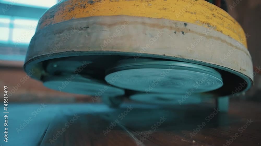 Abrasive discs of yellow floor polishing machine stands down on dusty ...