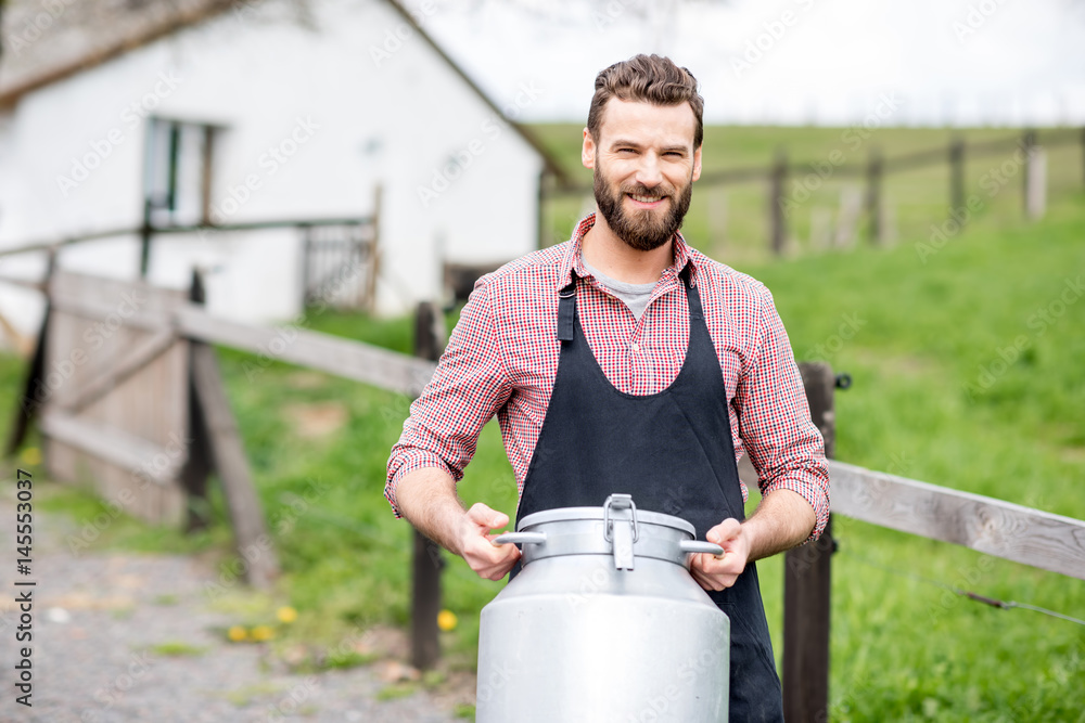 Portrait of a handsome milkman in apron walking with milk container ...