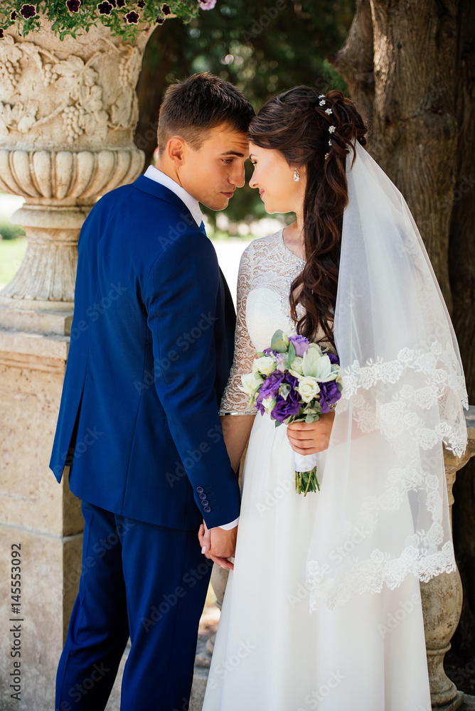 Yong beautiful bride and groom hugs outdoors. Bride embraces the groom ...