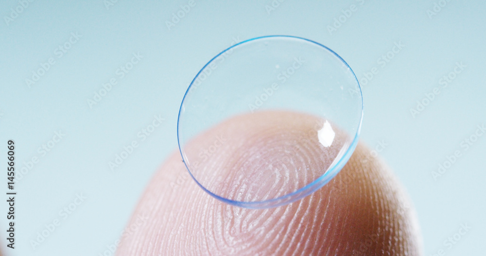 Macro shot of a finger holding a contact lens technology with a chip to ...