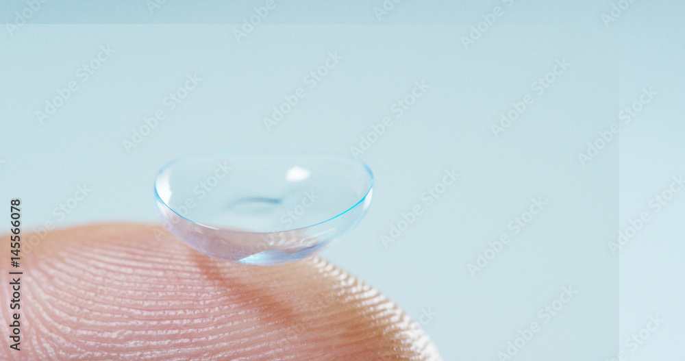 Macro shot of a finger holding a contact lens technology with a chip to ...