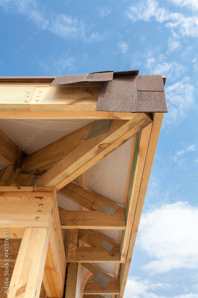 Corner of house with eaves, wooden beams and roof asphalt shingles ...