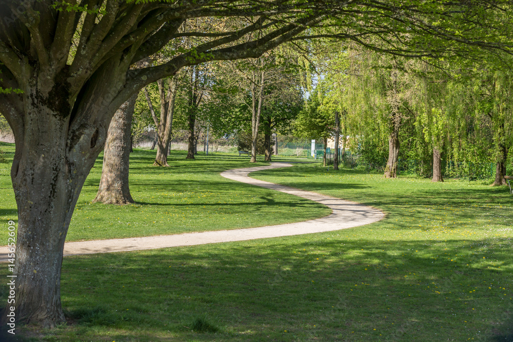 Sinuous path on an idyllic spring european park with green lawn and ...