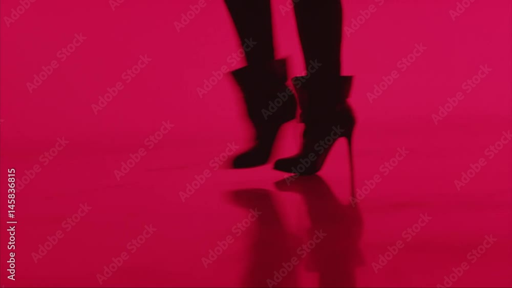 Woman struts in high heels in silhouette on reflective red background ...