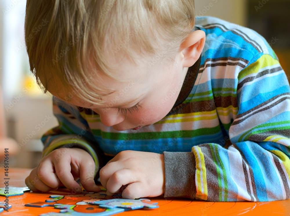 Little boy slouching while playing with puzzle. His wrong way of ...