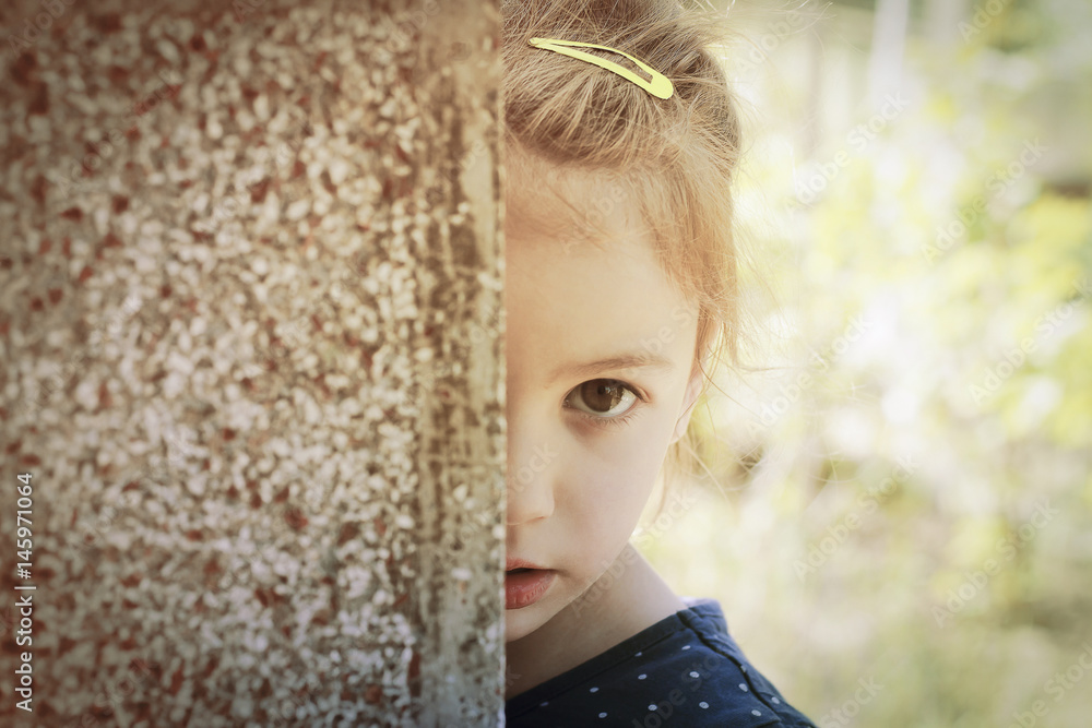 Cute little girls looking from behind wall. Stock Photo | Adobe Stock
