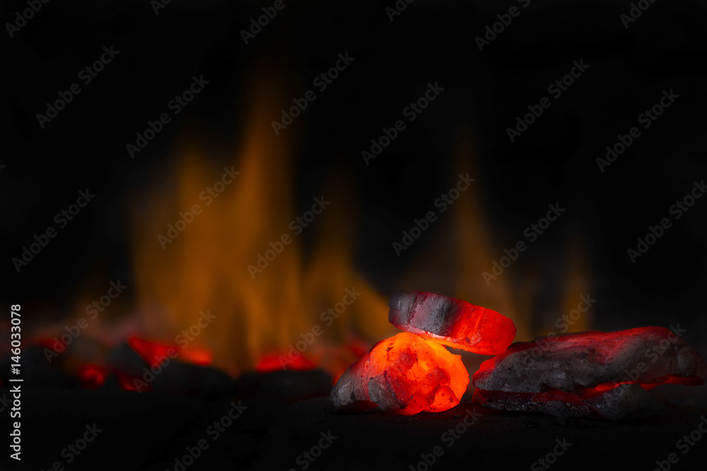 Red hot coal nugget in focus on dark background with flames. Background ...