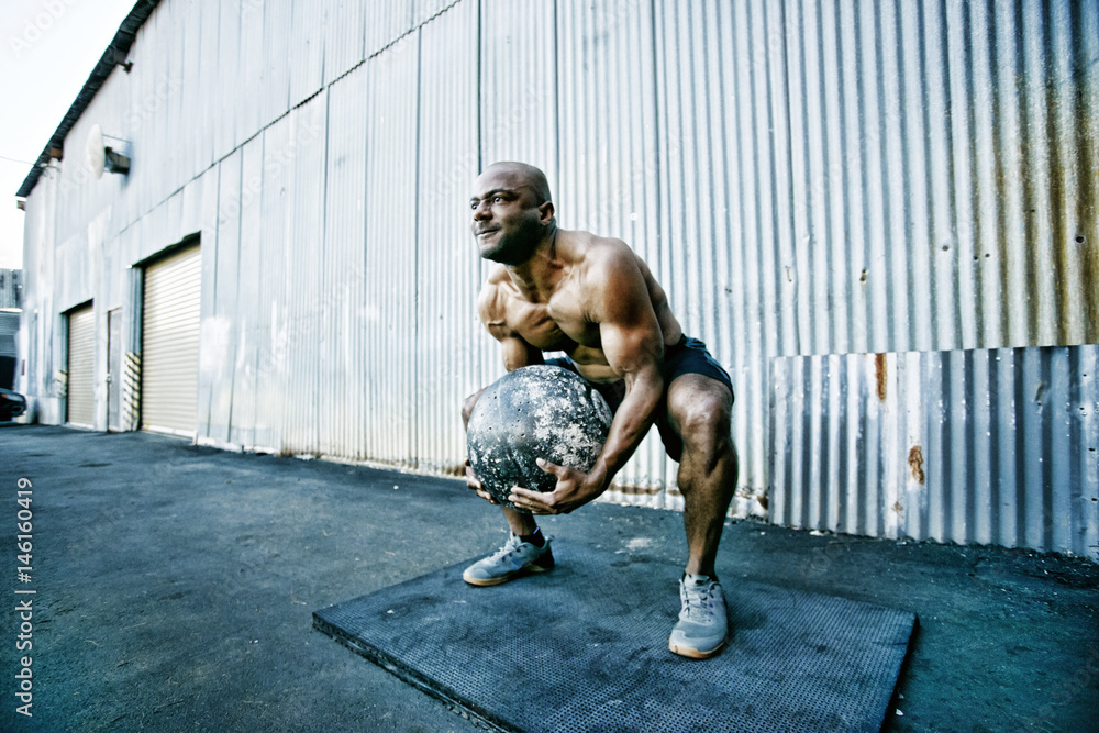 Black man lifting heavy ball outdoors Stock Photo | Adobe Stock