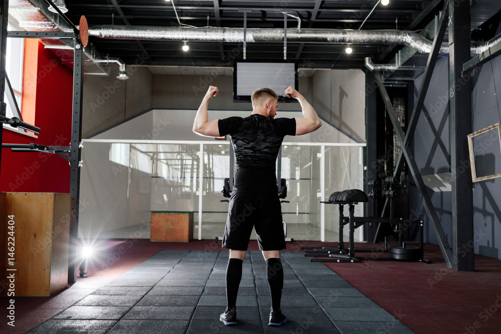 Young man preparing muscles before training, back view . Muscular ...
