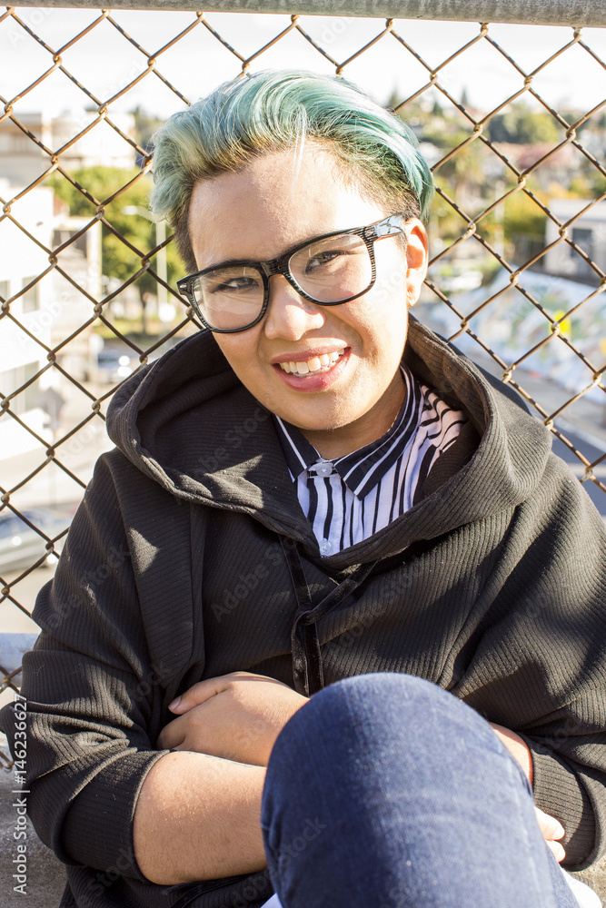 Smiling androgynous Asian woman leaning on chain-link fence Stock Photo ...