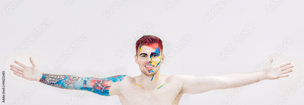 portrait of young attractive man with colored face paint on white ...