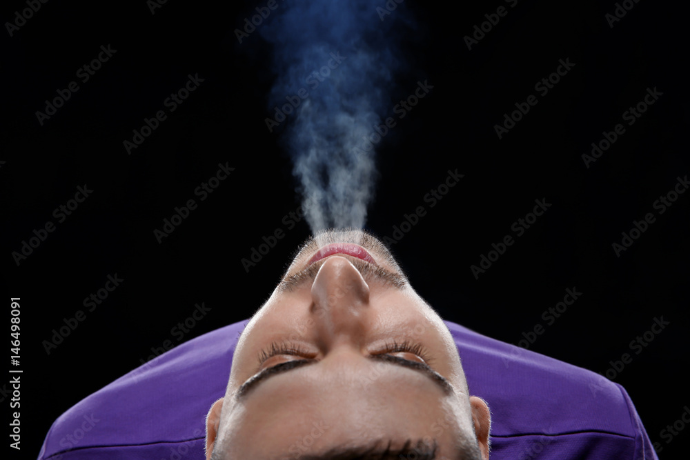Young man exhaling smoke on black background Stock Photo | Adobe Stock