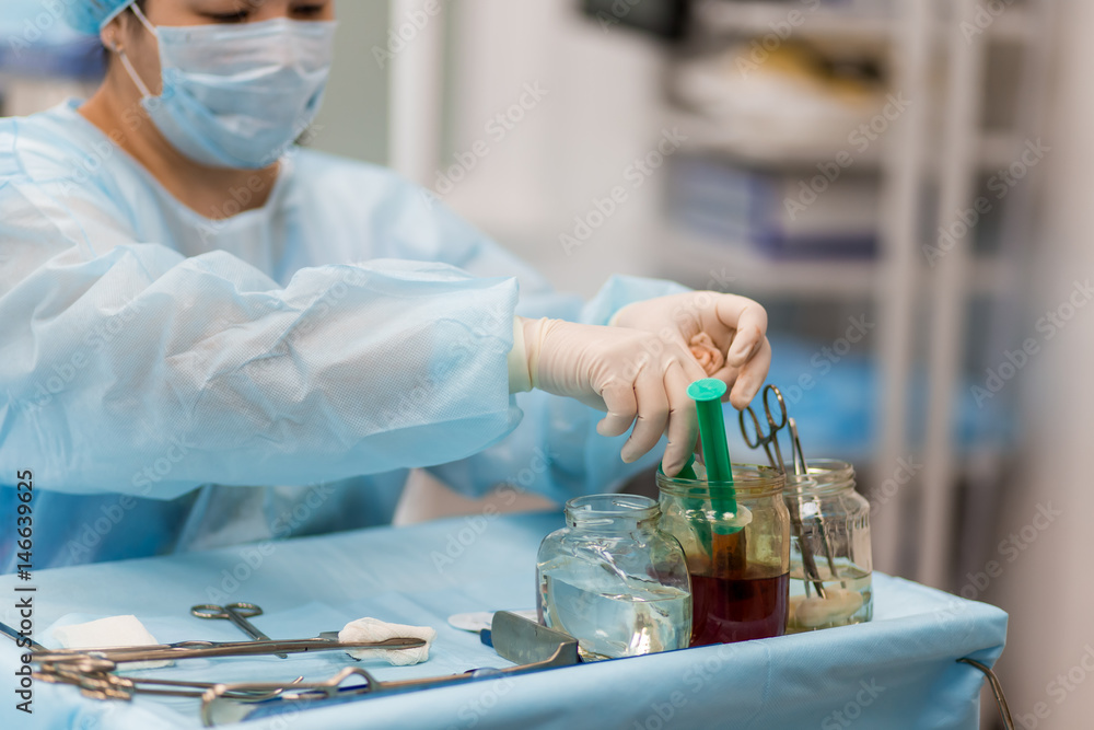 Nurse taking surgical instrument for group of surgeons at background ...
