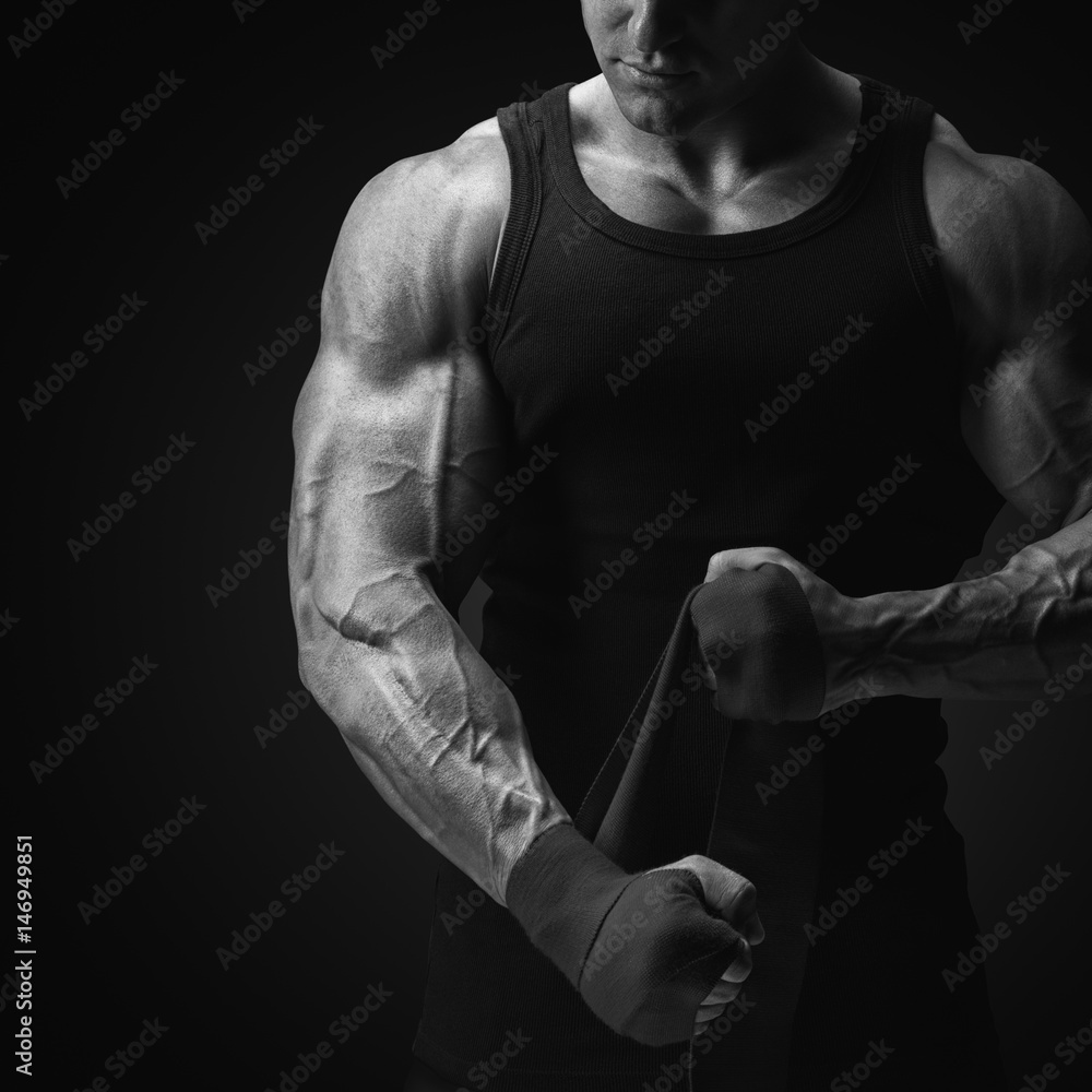 Croped shot of strong man wrap hands on black background Man is ...