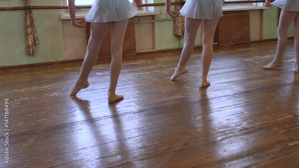 Girls in ballet shoes do exercises in ballet class in frayed ballet ...