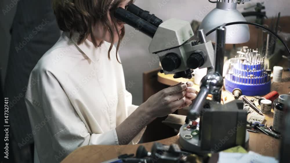 Vidéo Stock Side view of a woman jeweller examining a ring under a ...