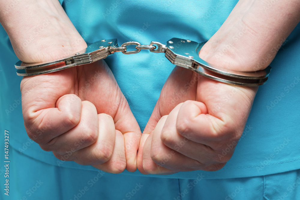 Doctor in blue uniform with stethoscope attached to handcuffed at the ...