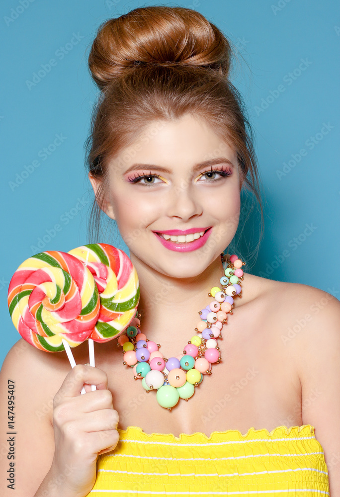 Portrait of a beautiful young woman with candy on a blue background ...