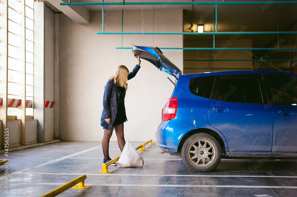 blonde woman in raincoat and pantyhose stacks purchases from grocery ...