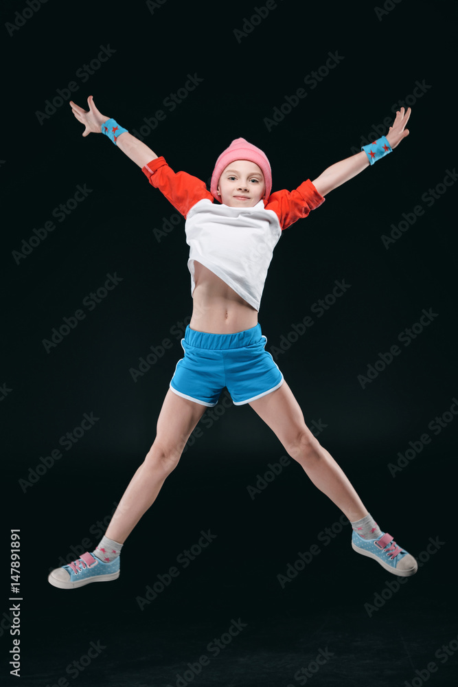 Smiling sporty girl jumping isolated on black, activities for children ...