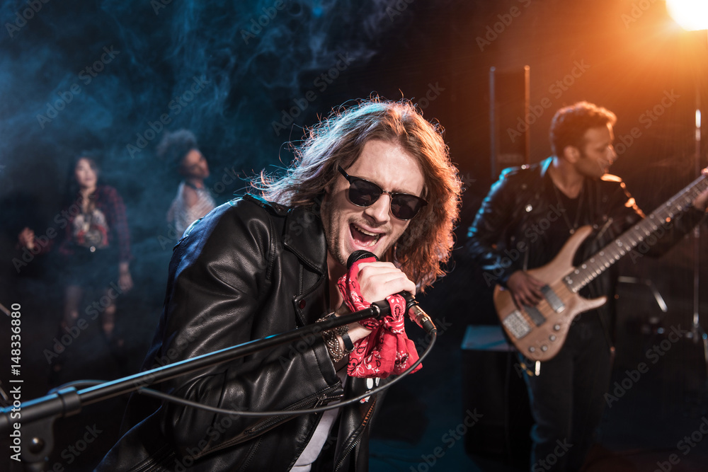 Male singer with microphone and rock and roll band performing hard rock ...