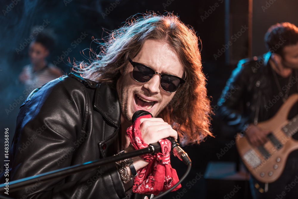 Male singer with microphone and rock and roll band performing hard rock ...