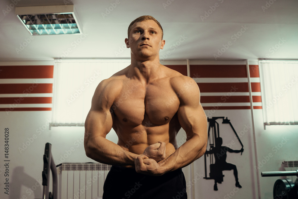 young muscular bodybuilder posing showing the biceps in the gym Stock ...