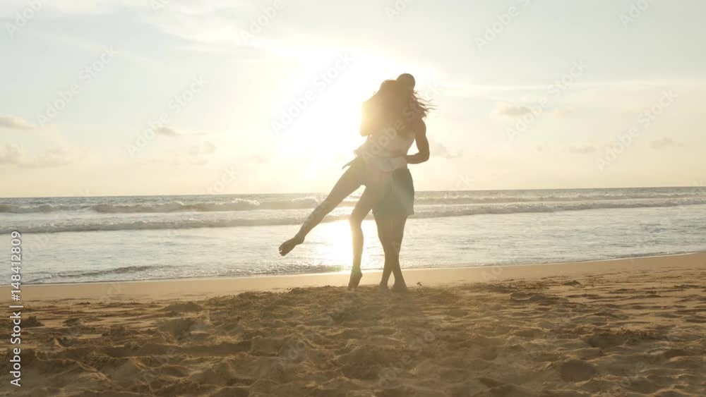 Young couple is running on the beach, man hug and spin around his woman ...