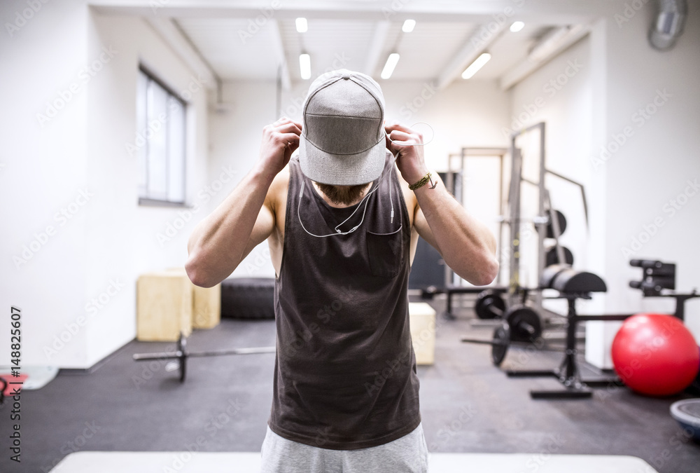 Young athlete wearing cap, using earphones in gym Stock Photo | Adobe Stock
