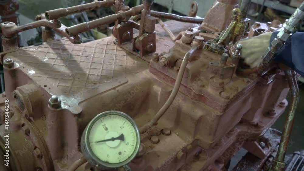 The worker is testing the gearbox of a large tractor. Repair of gearbox ...