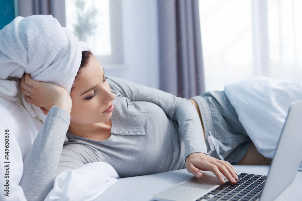 smiley young woman lying in her bed with laptop Stock Photo | Adobe Stock