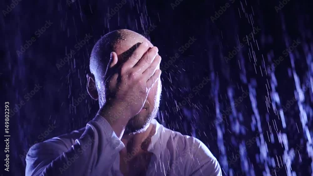 A bald man in the rain in a bad mood wipes her face and head with his ...