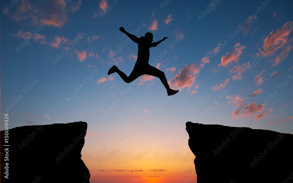 Man jumping across the gap from one rock to cling to the other. Man ...