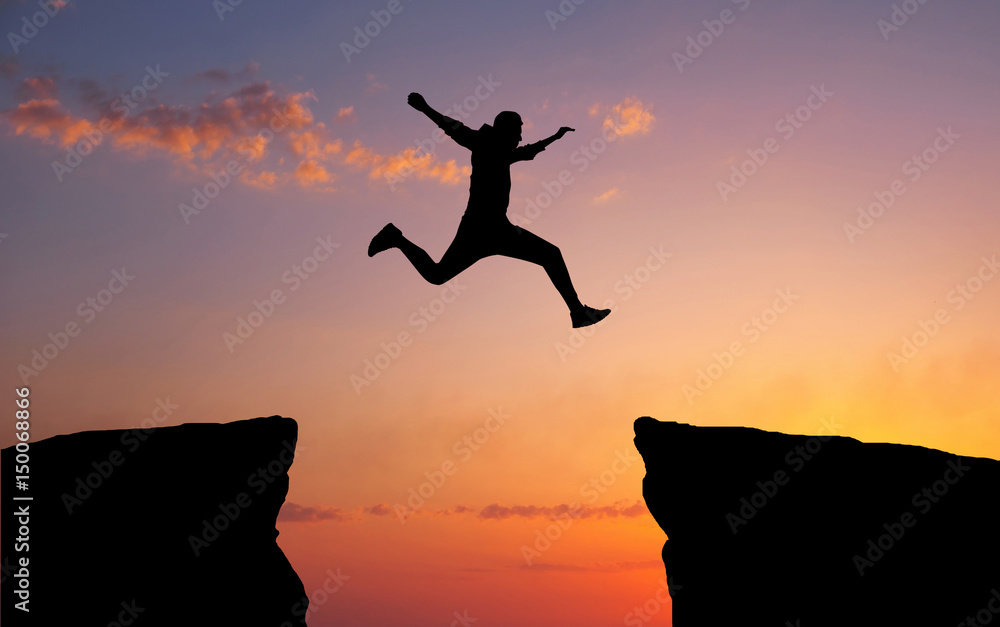 Man jumping across the gap from one rock to cling to the other. Man ...