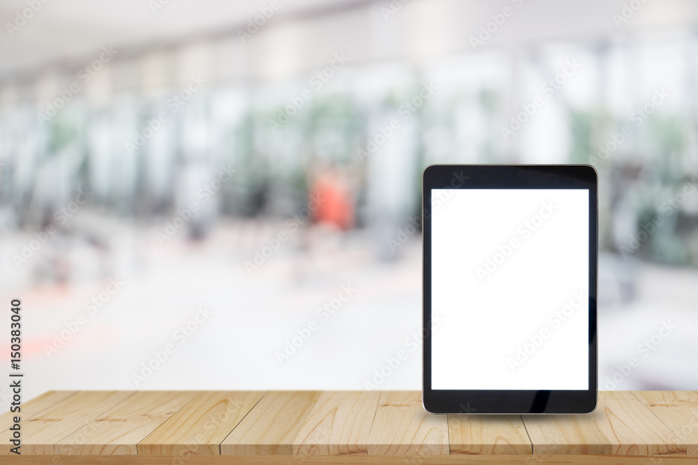 Tablet on wood table space platform and fitness gym background. Blank ...