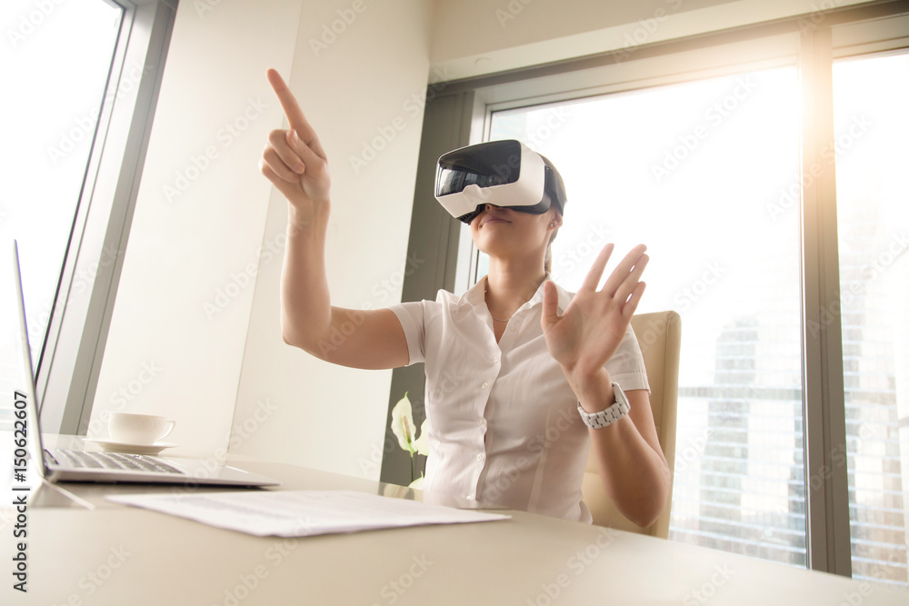 Business woman in office wearing virtual reality glasses and interacts ...
