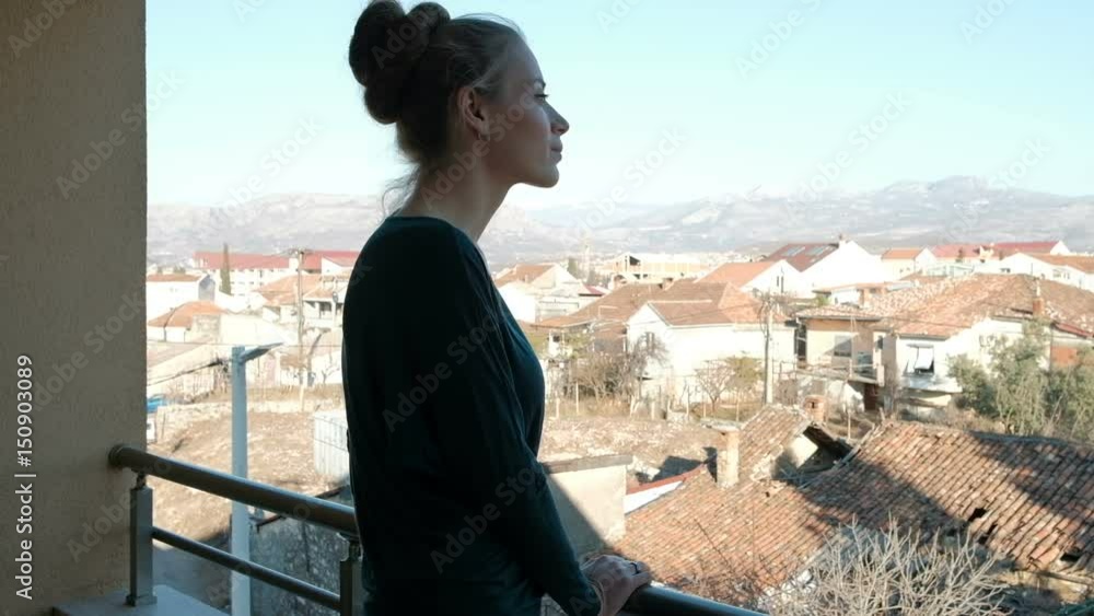 Young woman admires the landscape on balcony in her home. Beautiful ...